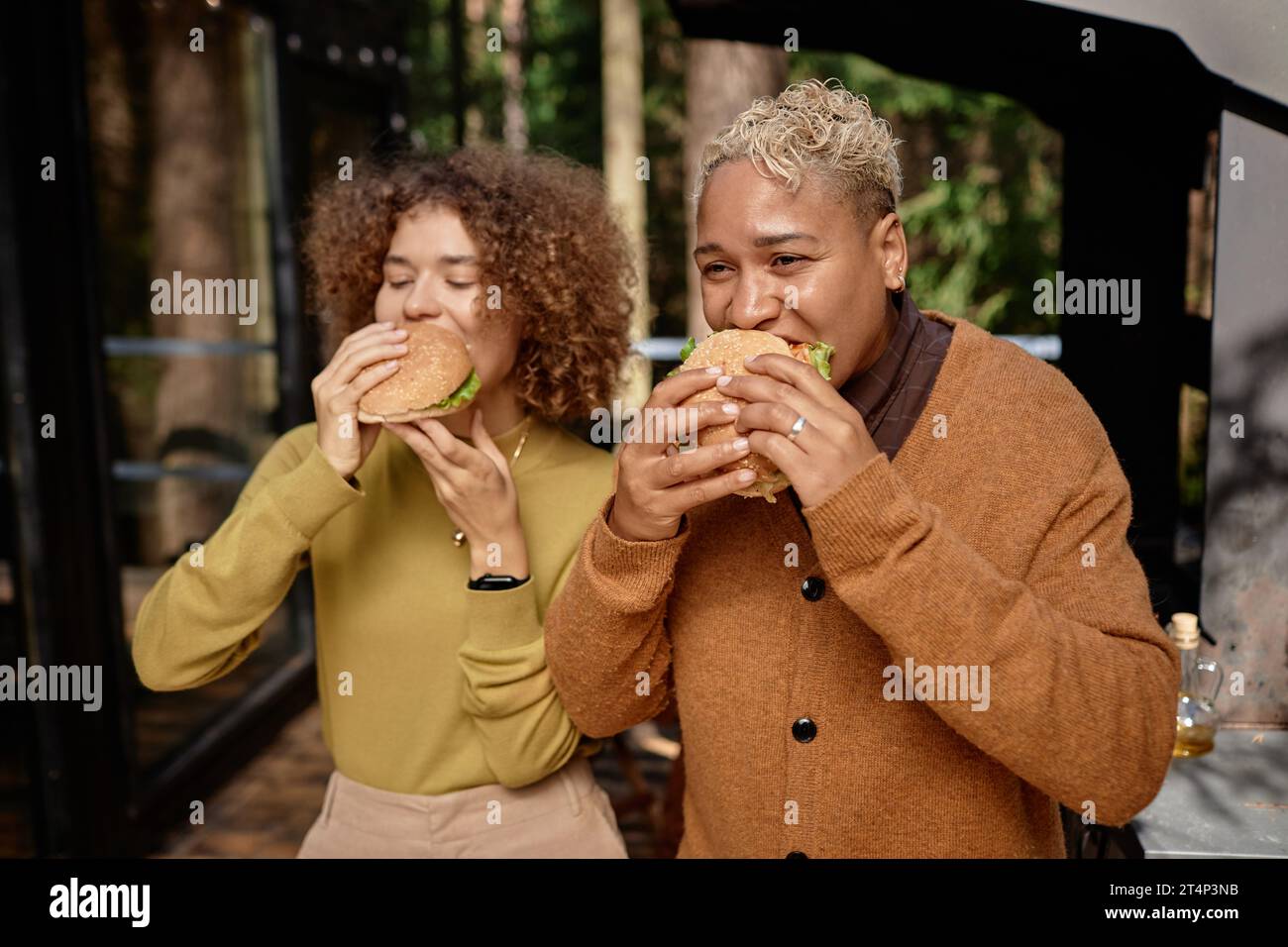 Young women eating homemade burgers at barbecue party Stock Photo - Alamy
