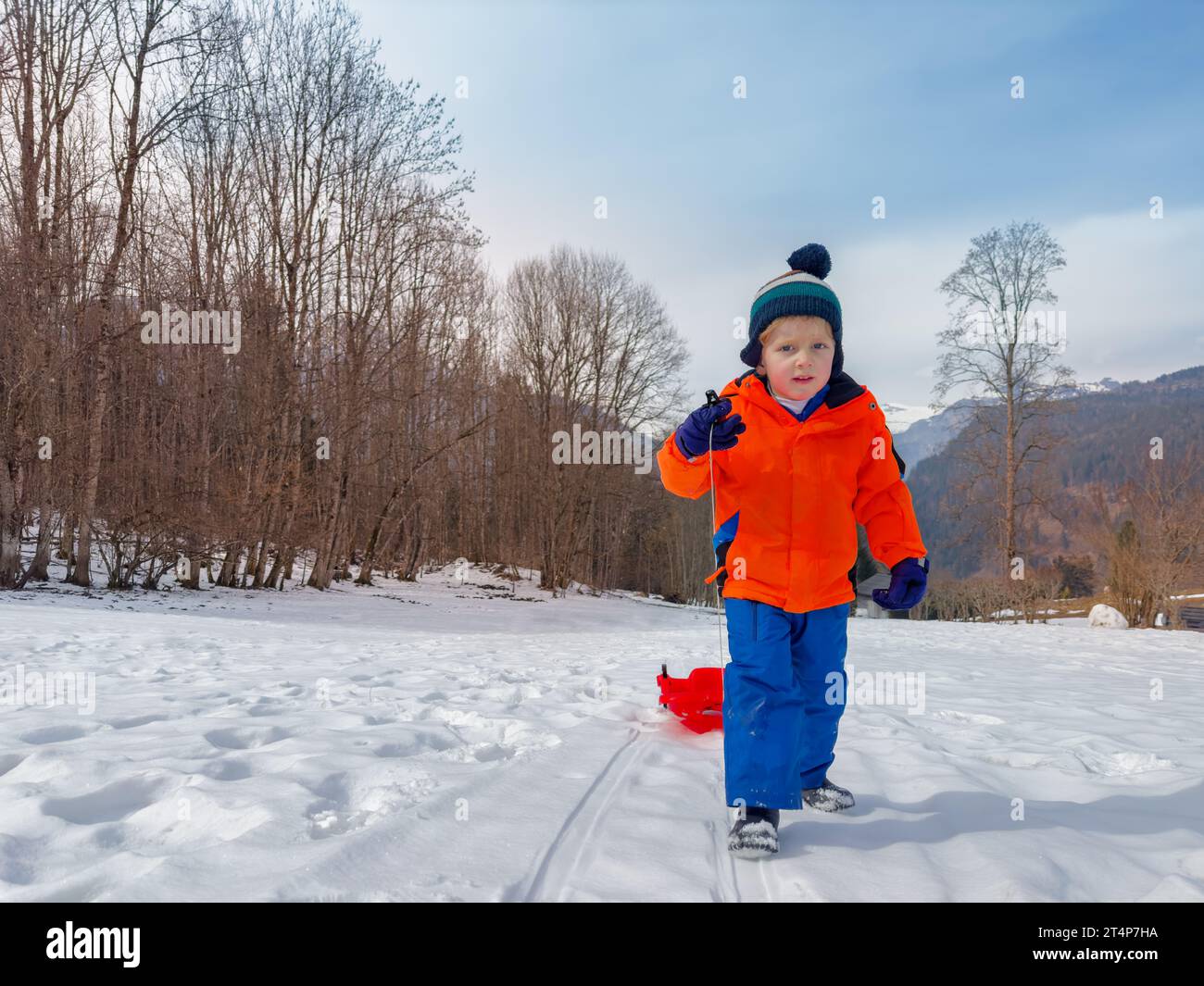 Little boy in winter outfit pull red sledge mounting the slope Stock ...