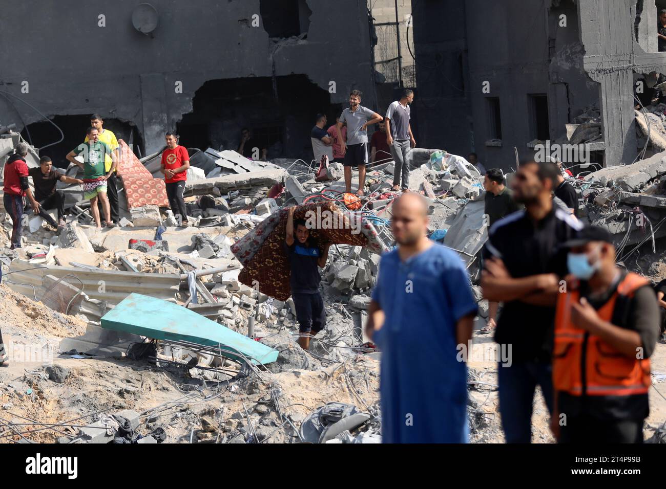 Palestinians walk among debris of buildings that were targeted by ...