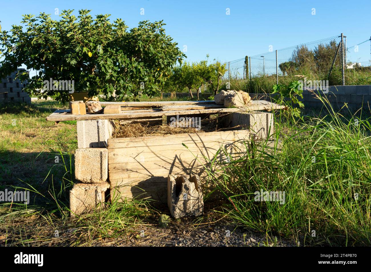 Artisanal composter built rustically, is full of branches and ...