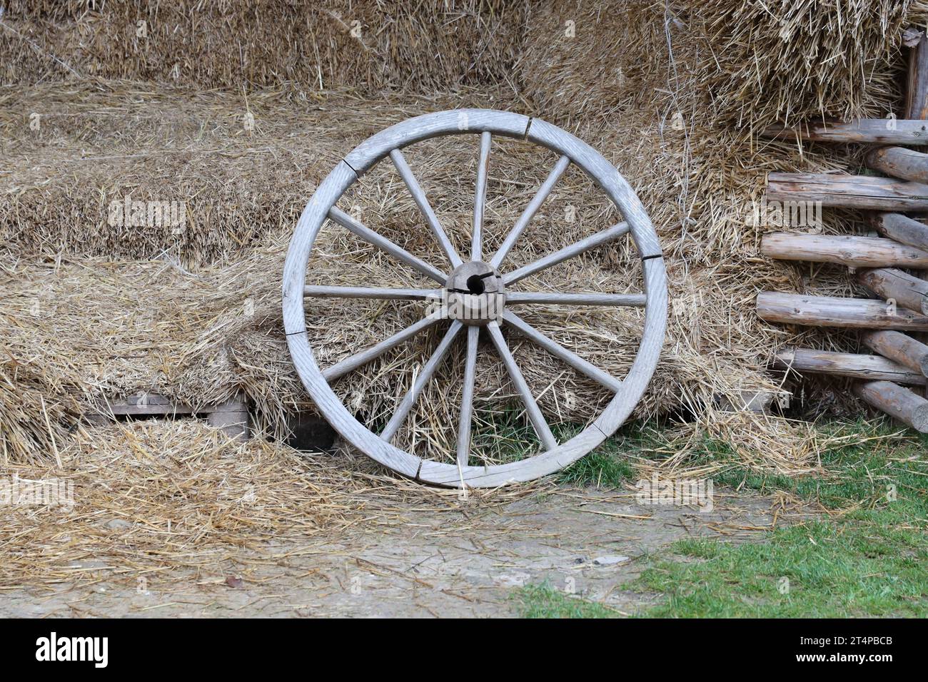 Place with stacks of hay cubes and rustic wooden wheels of old cart ...
