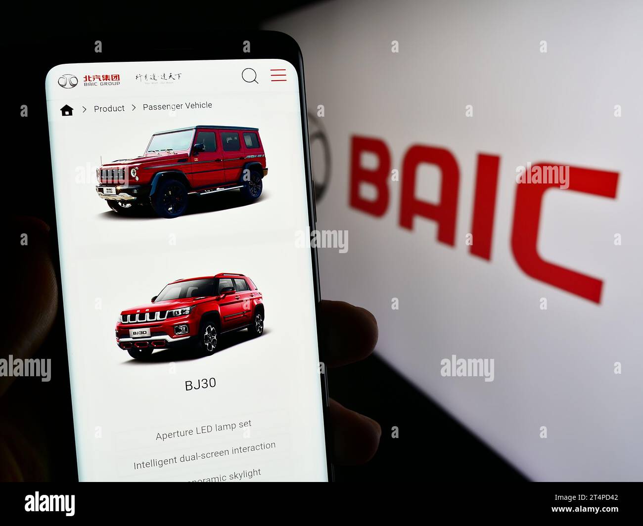 Person holding smartphone with web page of Chinese company Beijing Automotive Group Co. Ltd ...