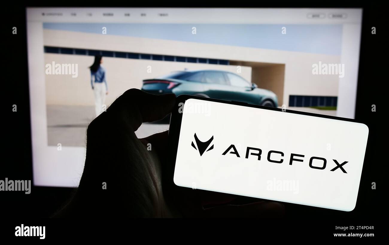 Person holding cellphone with logo of Chinese electric vehicle company Arcfox in front of ...