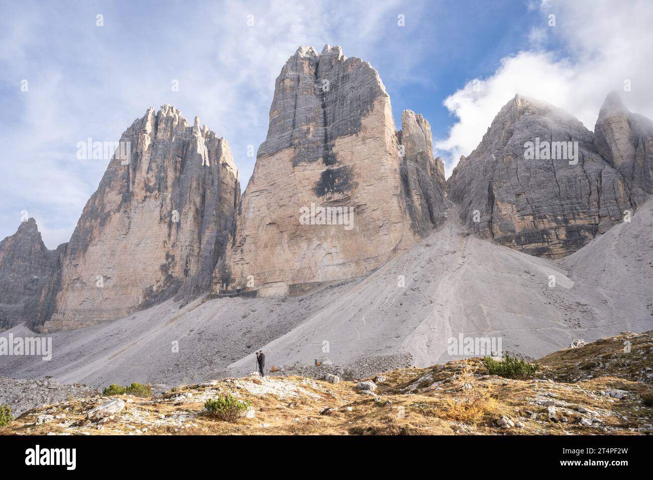Photographer standing below massive rock towers formation of Tre Cime ...