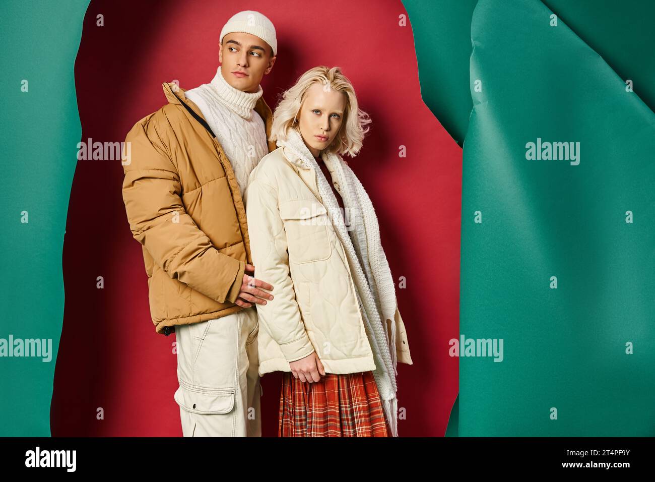 stylish man and woman in winter jackets posing together on torn ...