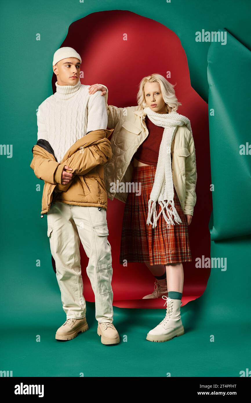 full length of stylish couple in winter jackets posing together on red ...