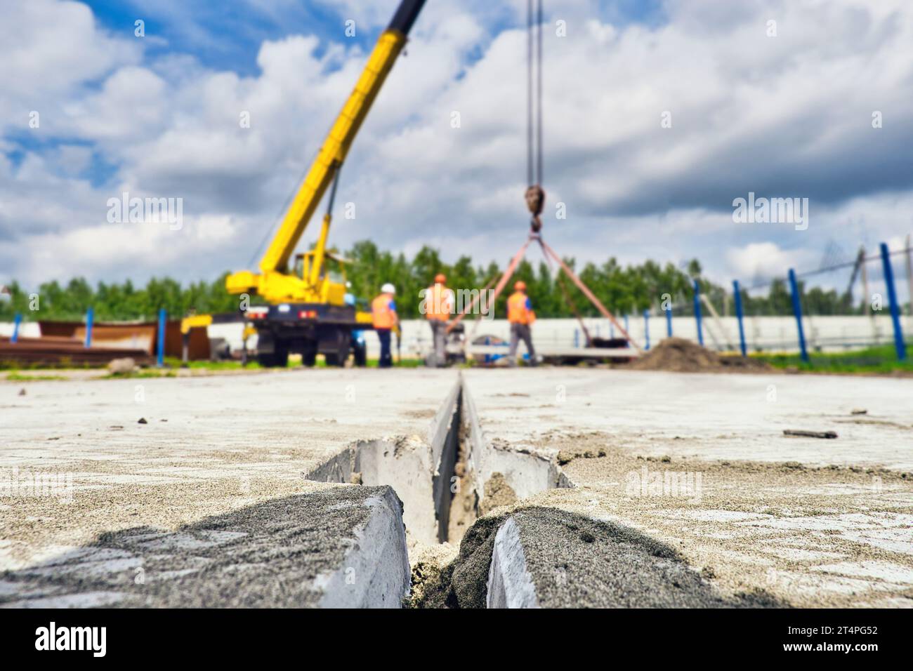 Builders in hard hats work on construction site. Team of workers lays ...