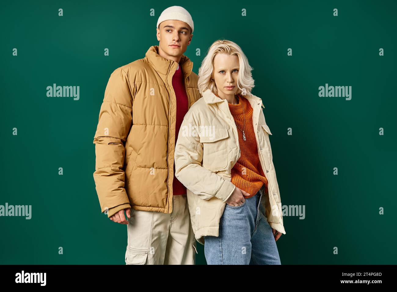 young man and woman in puffer jackets posing together on turquoise ...