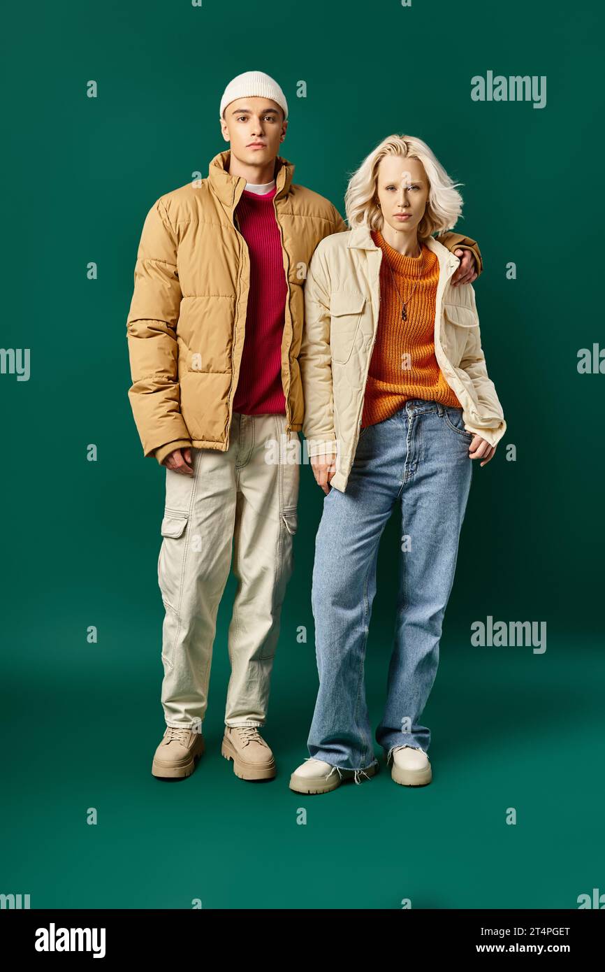 stylish couple in winter puffer jackets posing together on turquoise ...