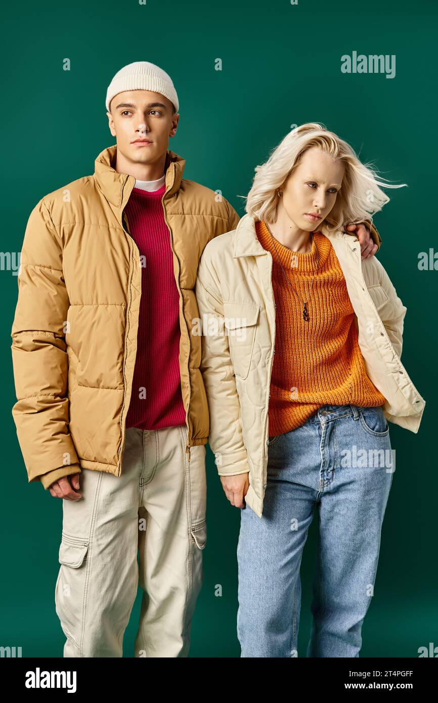 fashionable man in winter puffer jacket hugging woman and posing ...