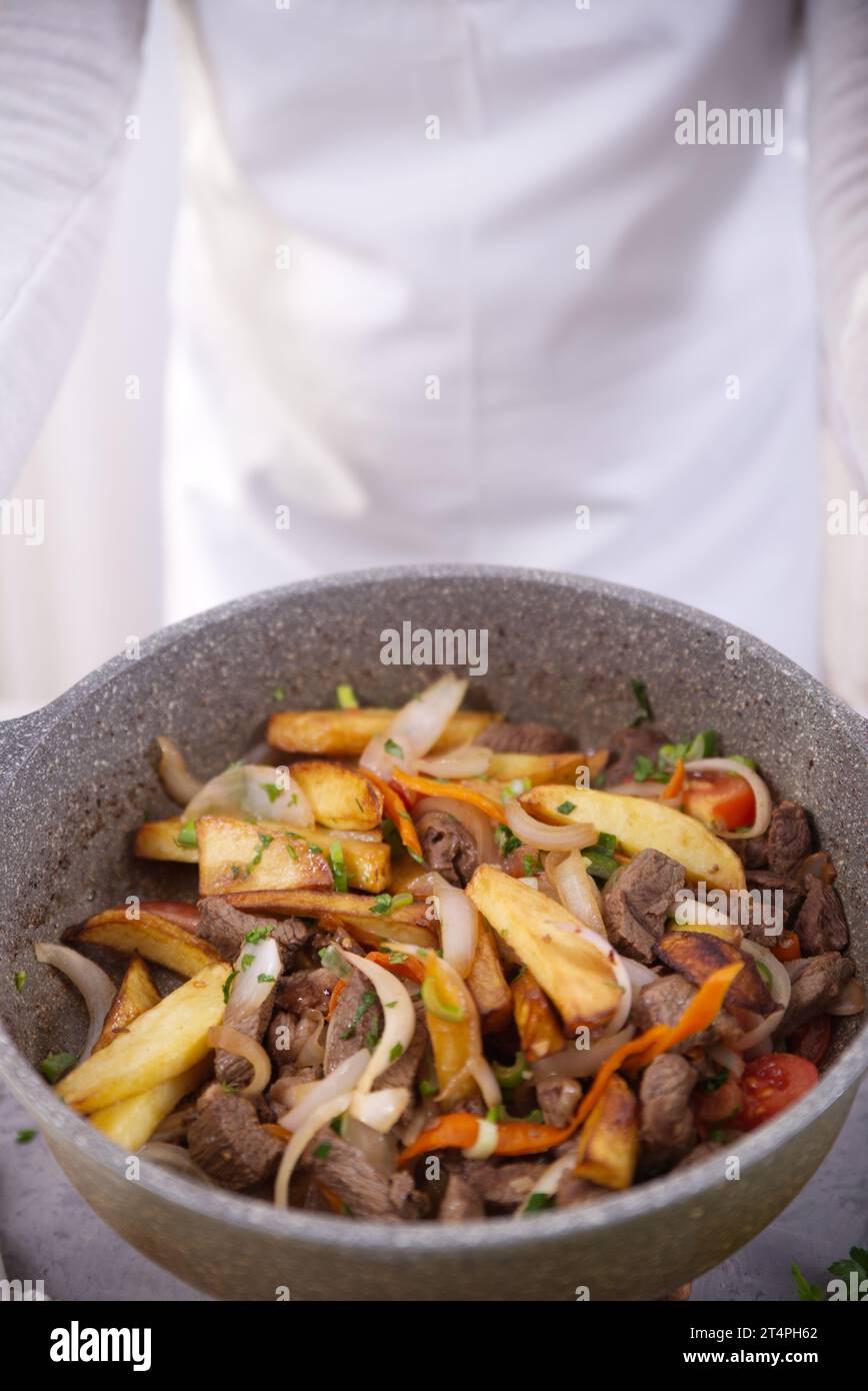 Hands holding casserole with a typical Peruvian dish called Lomo ...