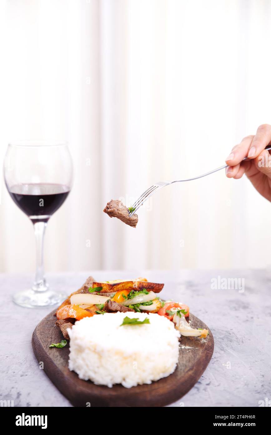 Hand picking up a fork with a piece of meat, from a typical Peruvian ...