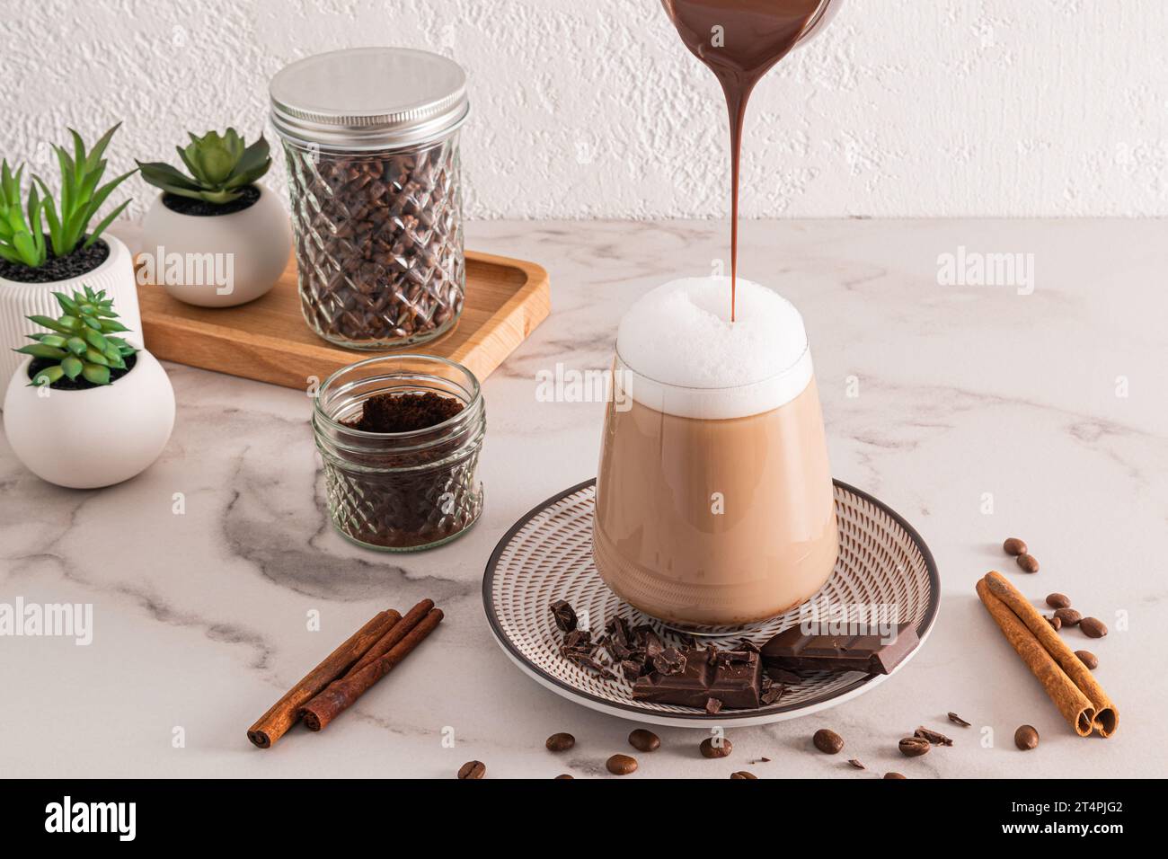 A jet of hot chocolate is poured into a large glass of coffee ...
