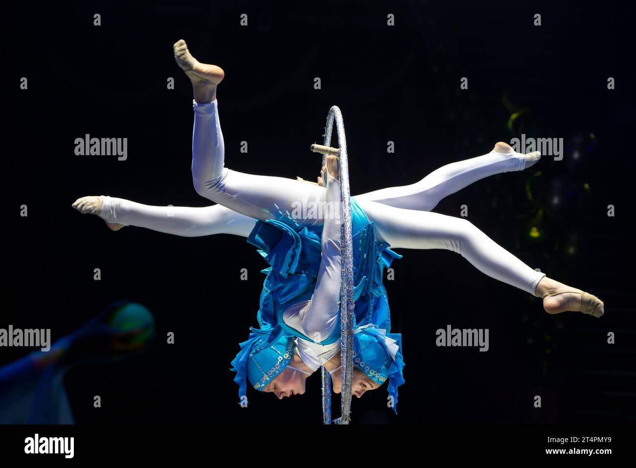 Two acrobat girls show a circus number on a dark background. Acrobatic ...