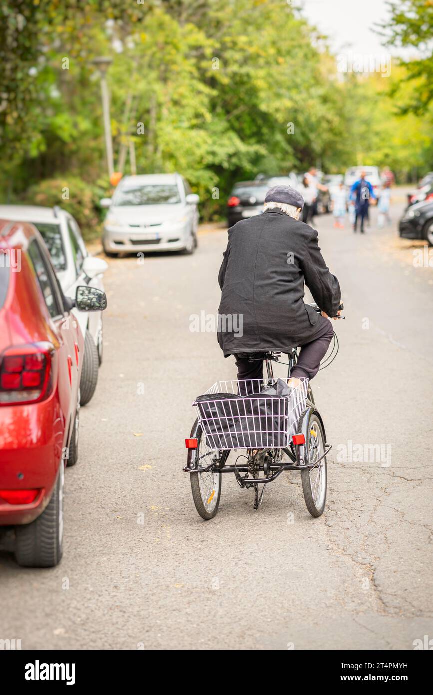 Elderly man riding tricycle, rear view. Active lifestyle of older ...