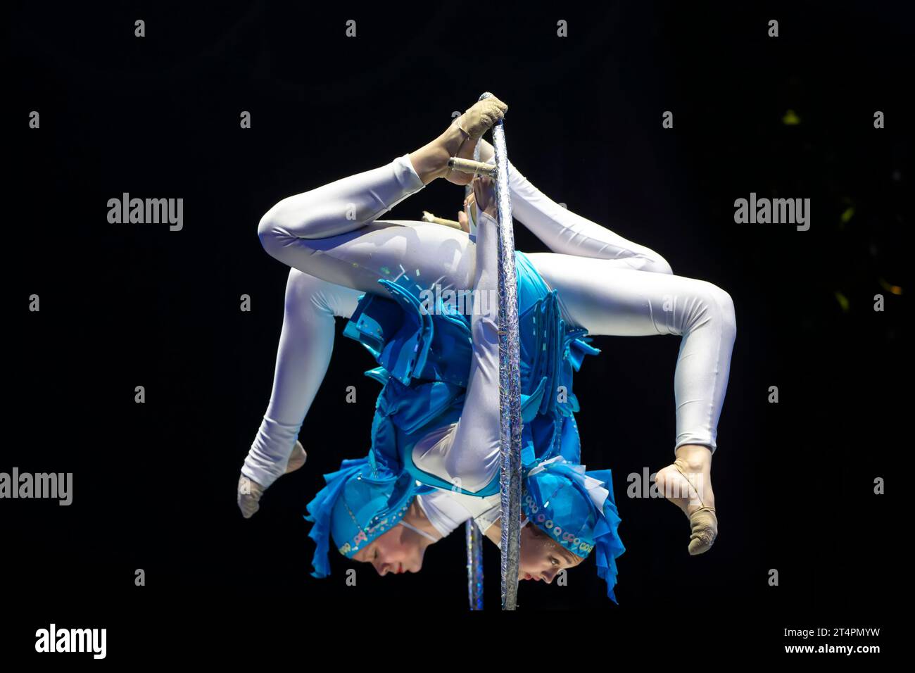 Two acrobat girls show a circus number on a dark background. Acrobatic ...