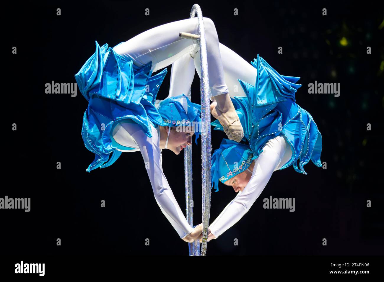 Two acrobat girls show a circus number on a dark background. Acrobatic ...