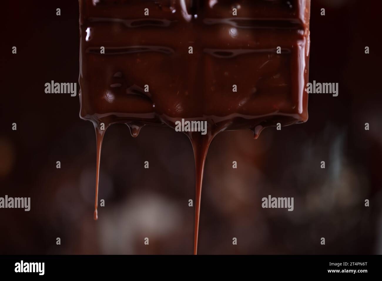 Melted chocolate drips down on a brown background Stock Photo - Alamy
