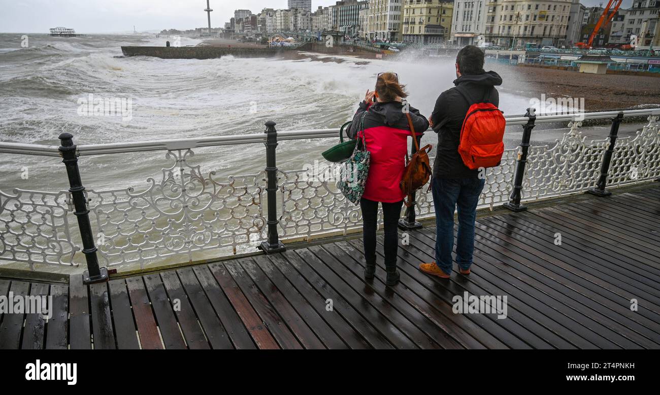 Brighton UK 1st November 2023 - Visitors on the pier watch waves ...