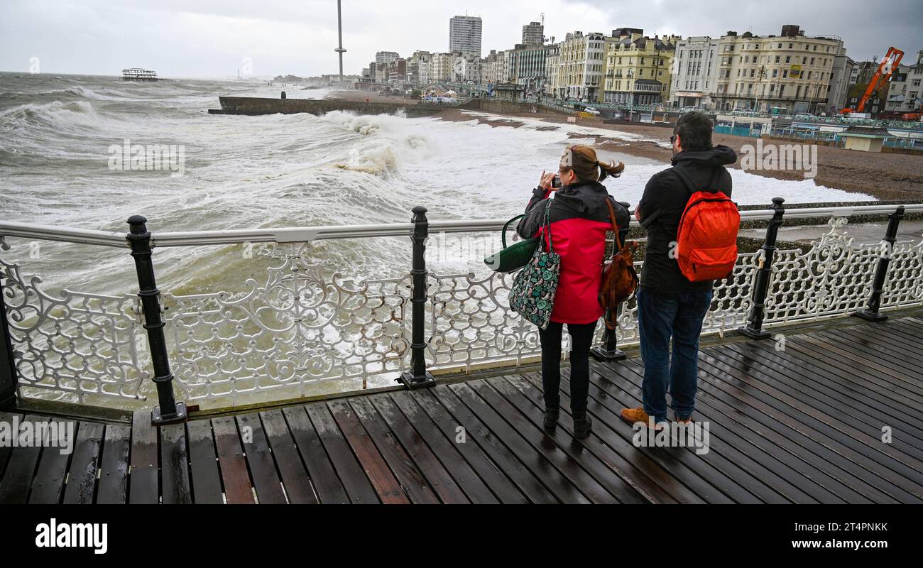Brighton UK 1st November 2023 - Visitors on the pier watch waves ...