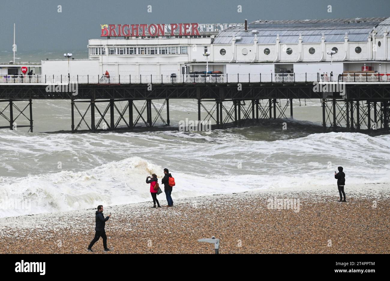 Brighton UK 1st November 2023 - Visitors watch waves crashing onto ...