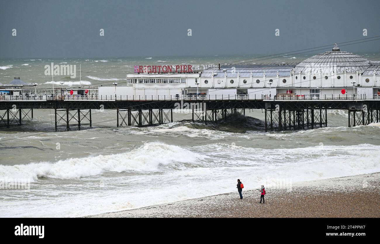 Brighton UK 1st November 2023 - Visitors watch waves crashing onto ...