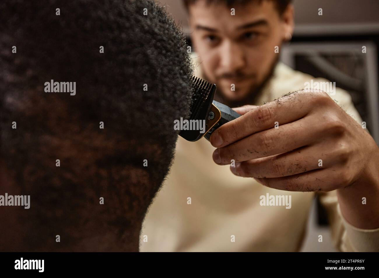 Barber using trimmer to shave the head of customer during his visit to ...