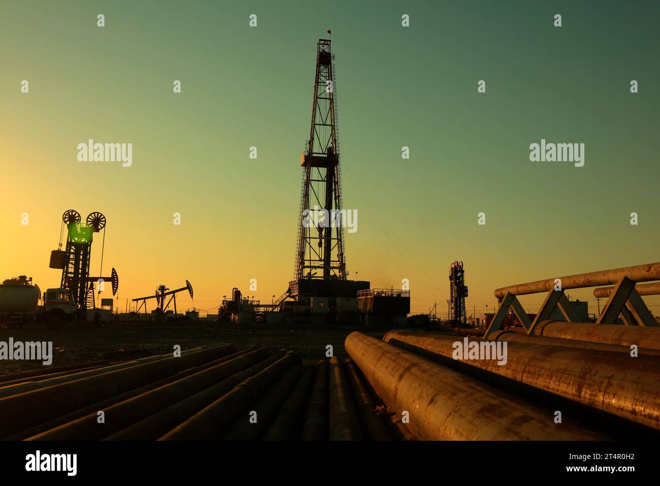 Oil drilling derrick and pipelines in oilfield Stock Photo - Alamy