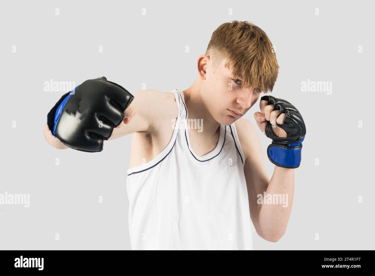 A caucasian teenage boy wearing MMA style boxing gloves punching Stock ...