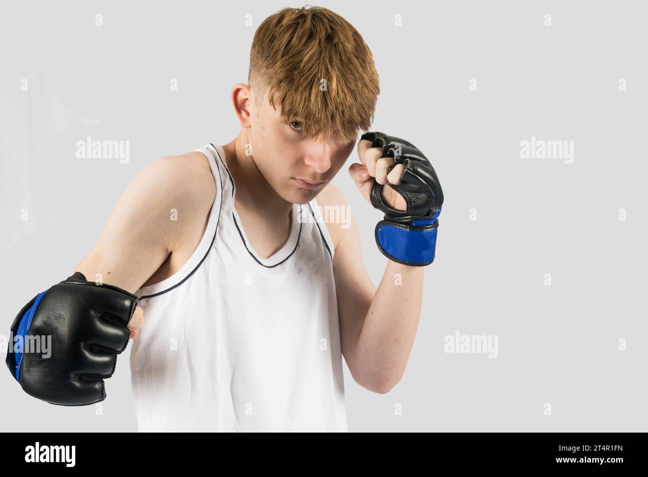 A caucasian teenage boy wearing MMA style boxing gloves punching Stock ...