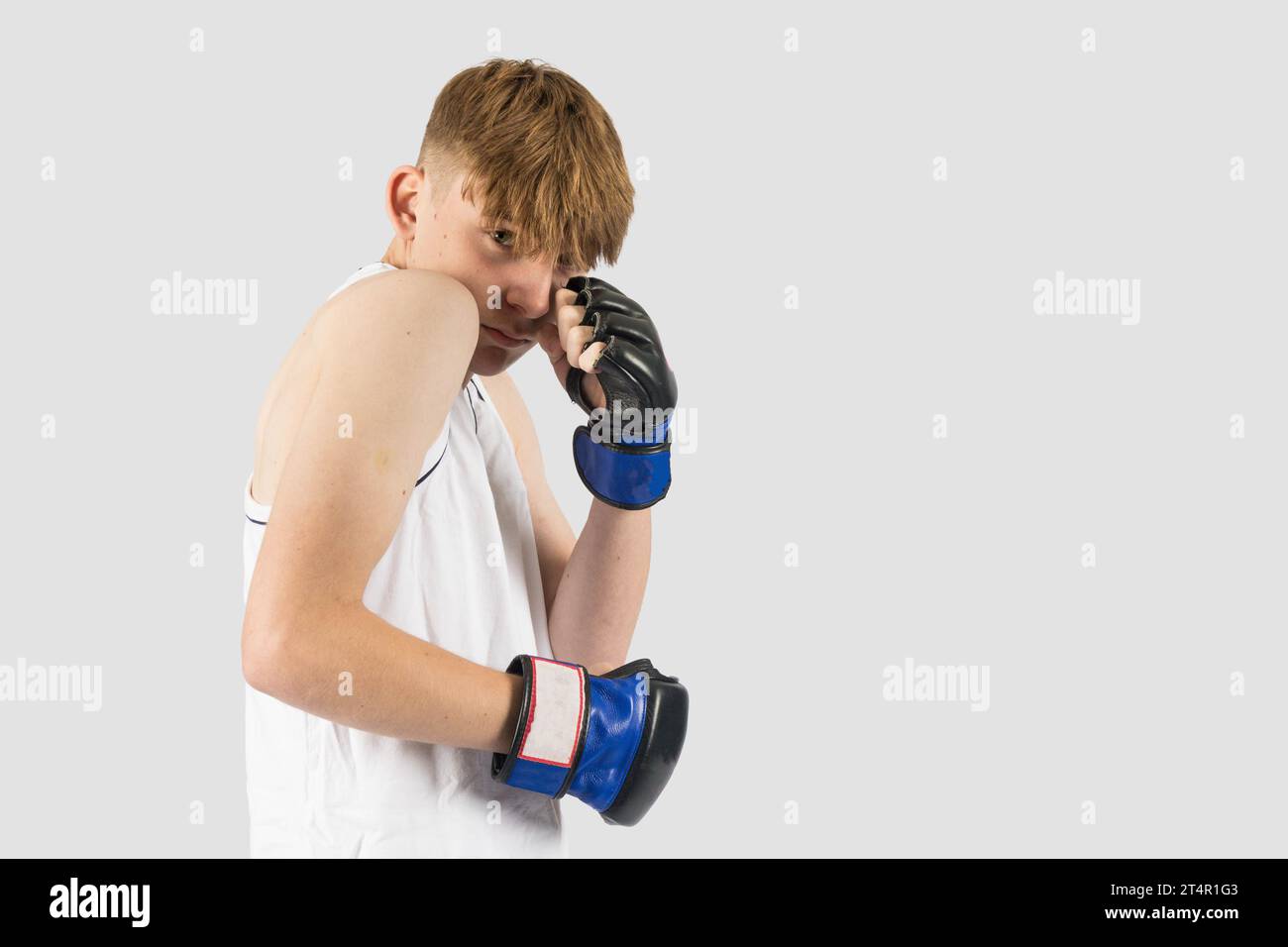 A caucasian teenage boy wearing MMA style boxing gloves on the ...