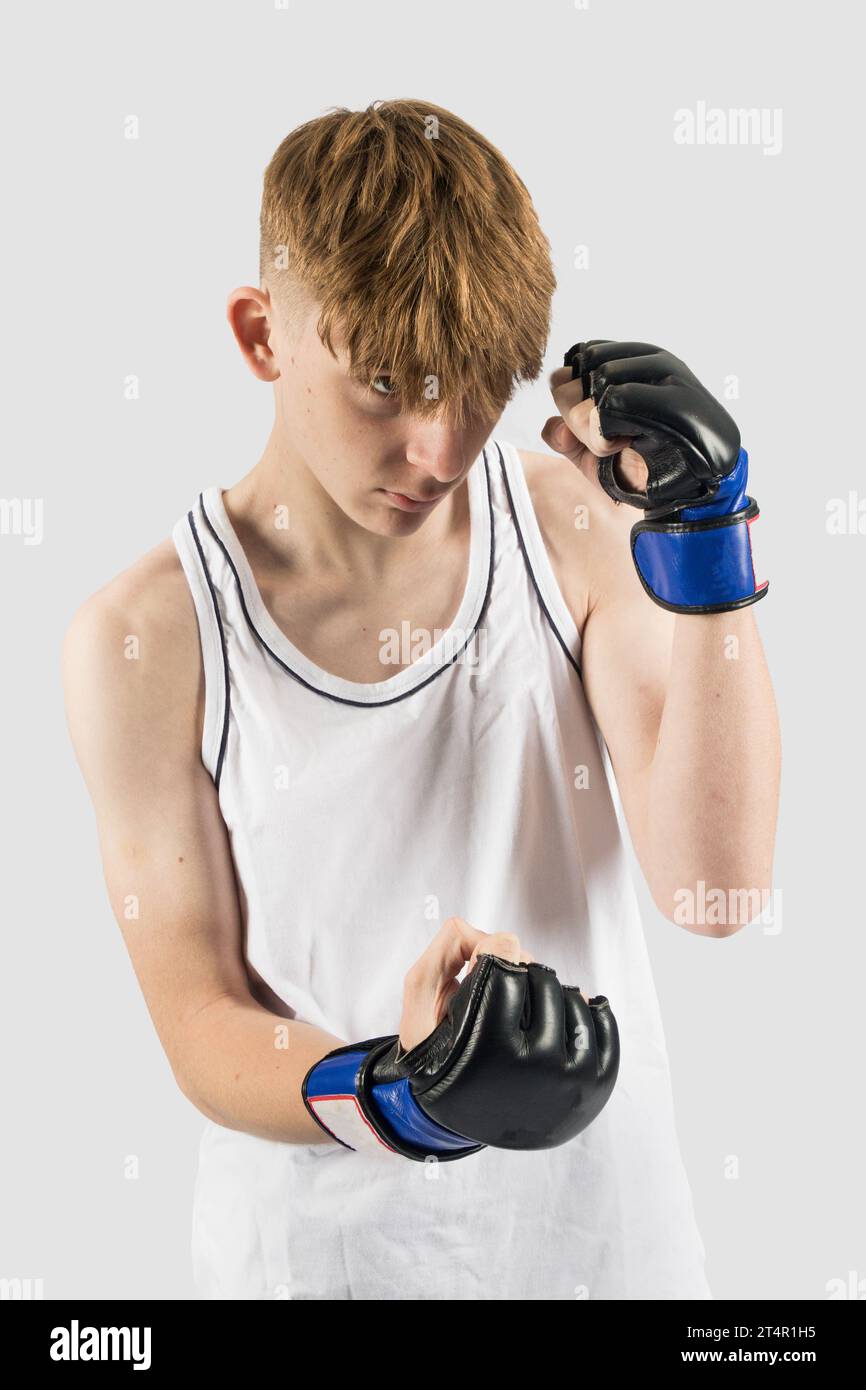 A caucasian teenage boy wearing MMA style boxing gloves punching Stock ...