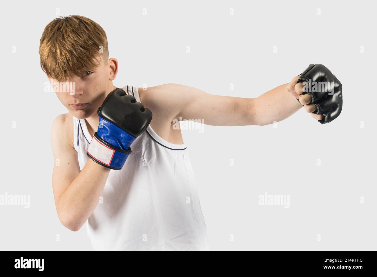 A caucasian teenage boy wearing MMA style boxing gloves punching Stock ...
