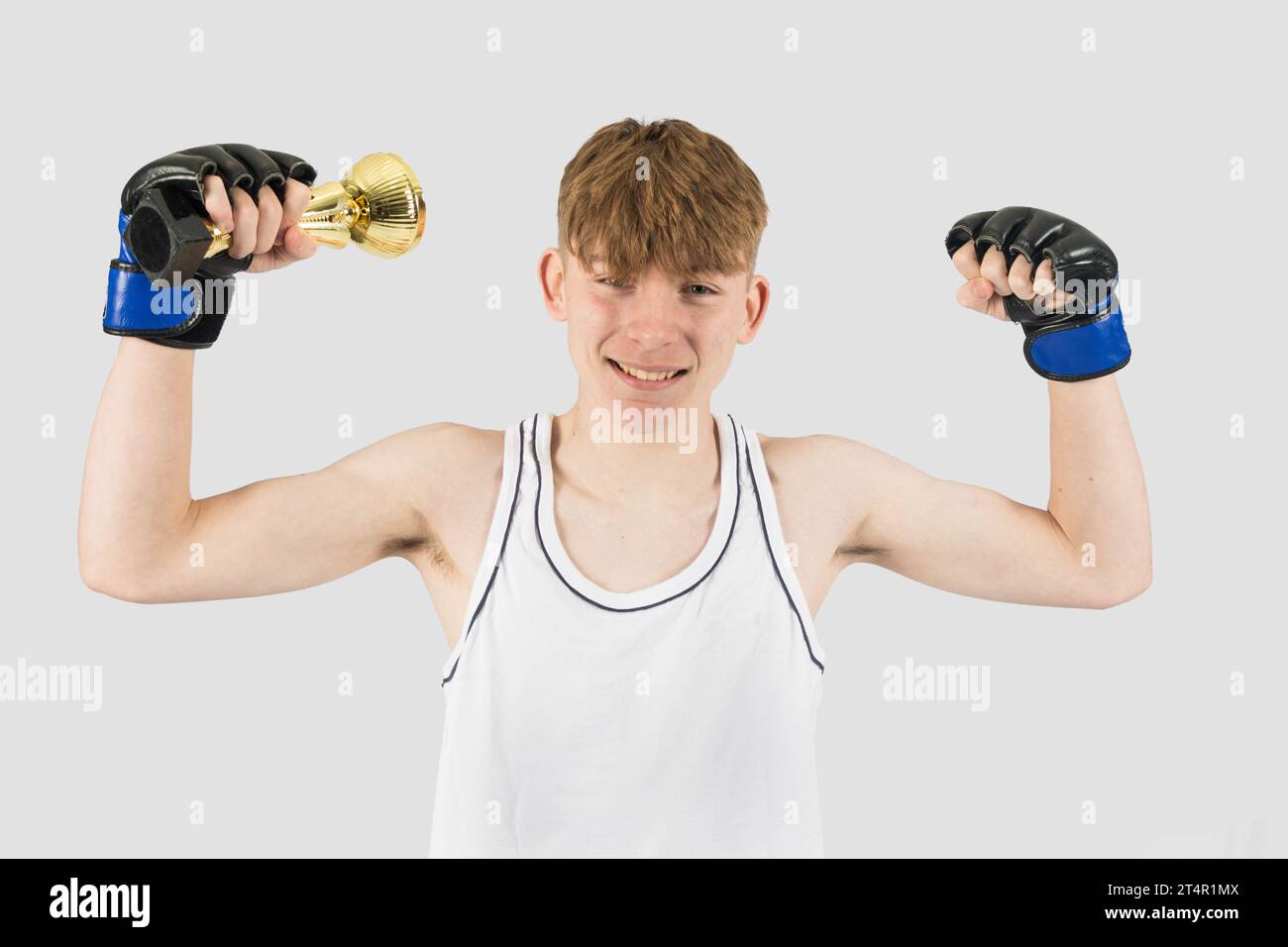 A caucasian teenage boy wearing MMA style boxing gloves celebrating ...