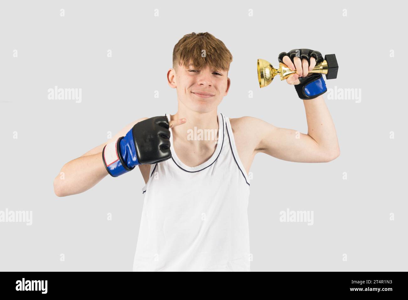 A caucasian teenage boy wearing MMA style boxing gloves celebrating ...