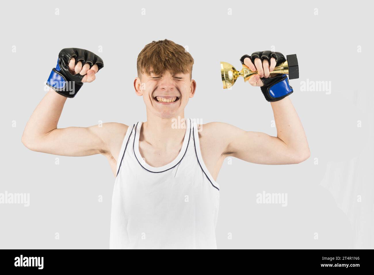 A caucasian teenage boy wearing MMA style boxing gloves celebrating ...