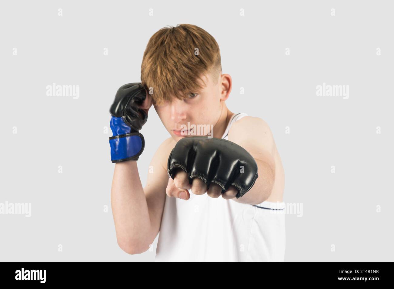A caucasian teenage boy wearing MMA style boxing gloves punching Stock ...