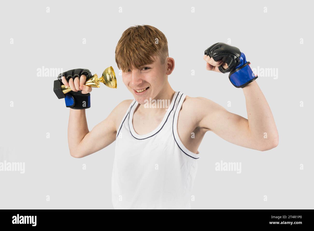 A caucasian teenage boy wearing MMA style boxing gloves celebrating ...