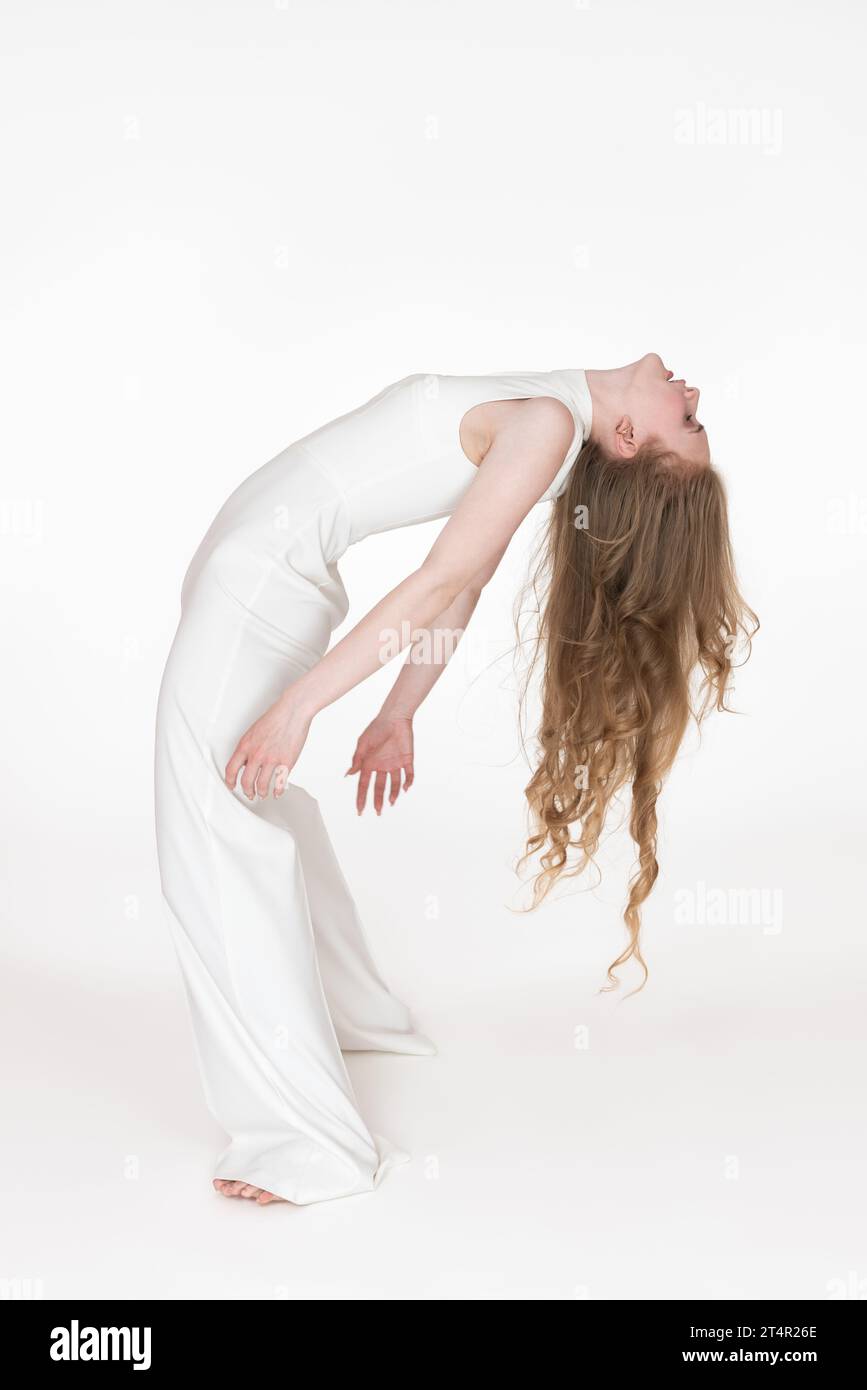 Flexible young blonde woman dancer with eyes closed bending over ...