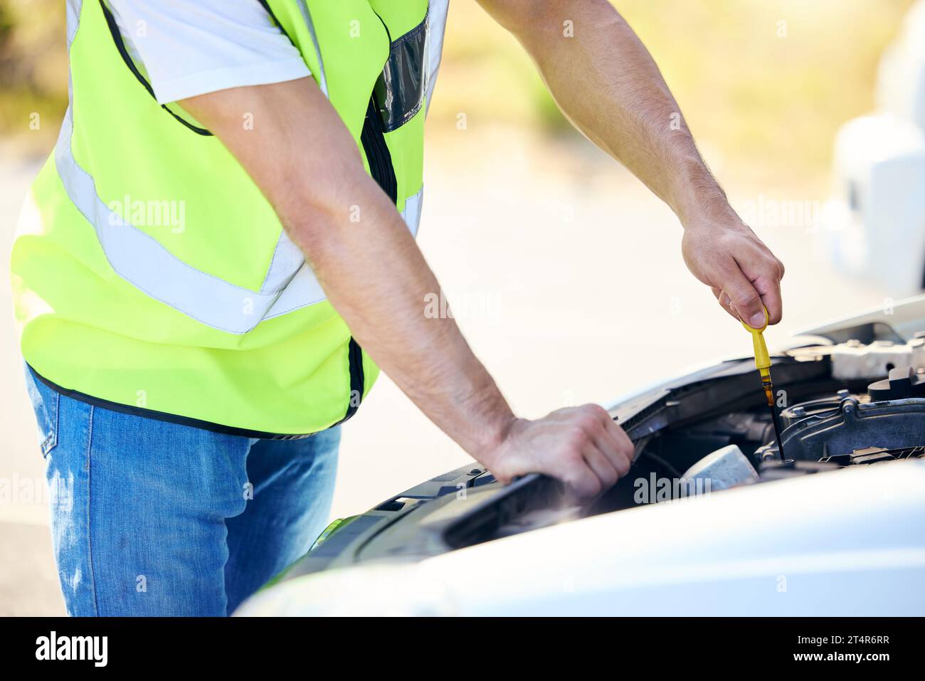 At your service. an unrecognizable man checking under the hood of his car after suffering a ...