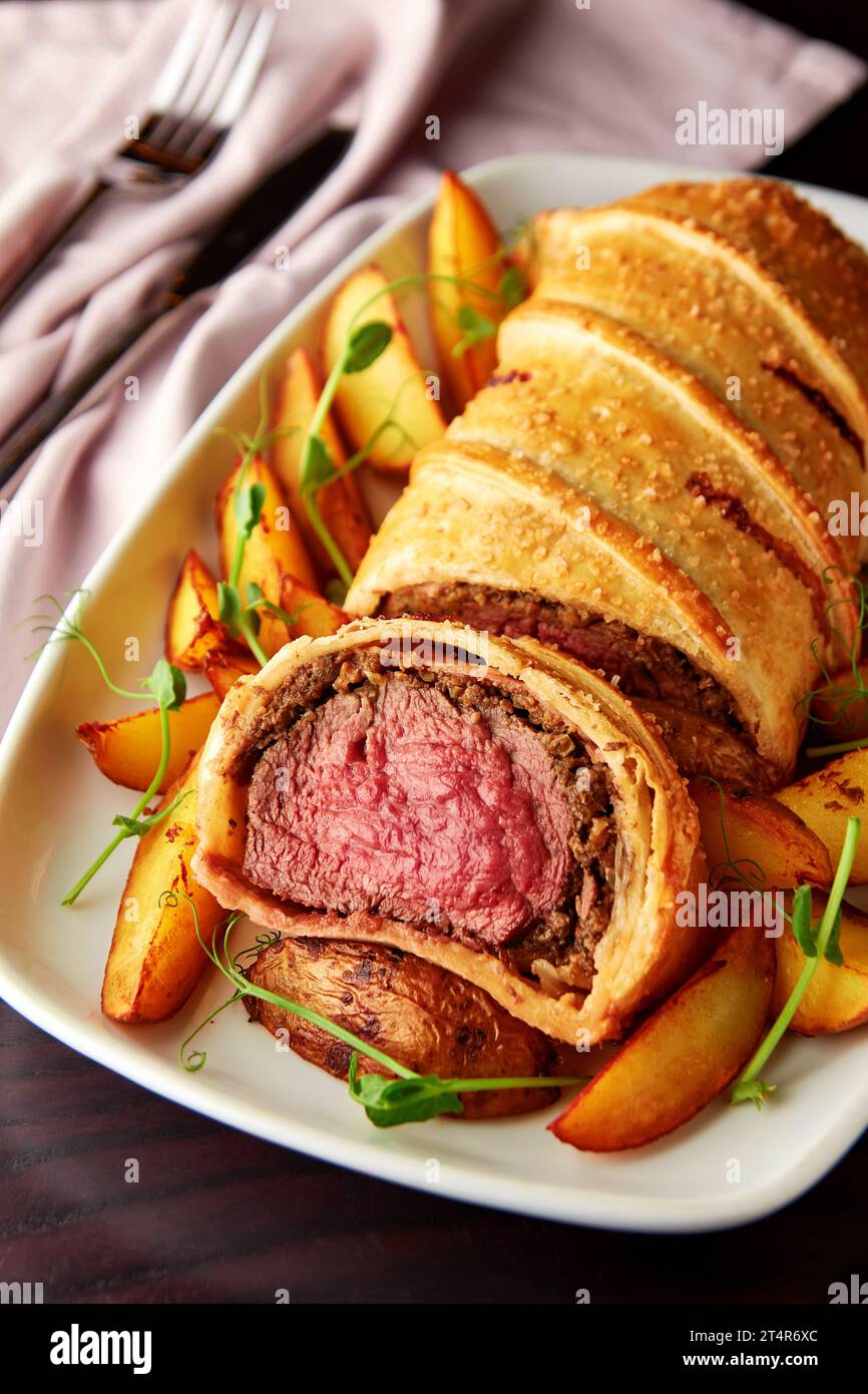 Delicious beef wellington served with baked potato and microgreens ...