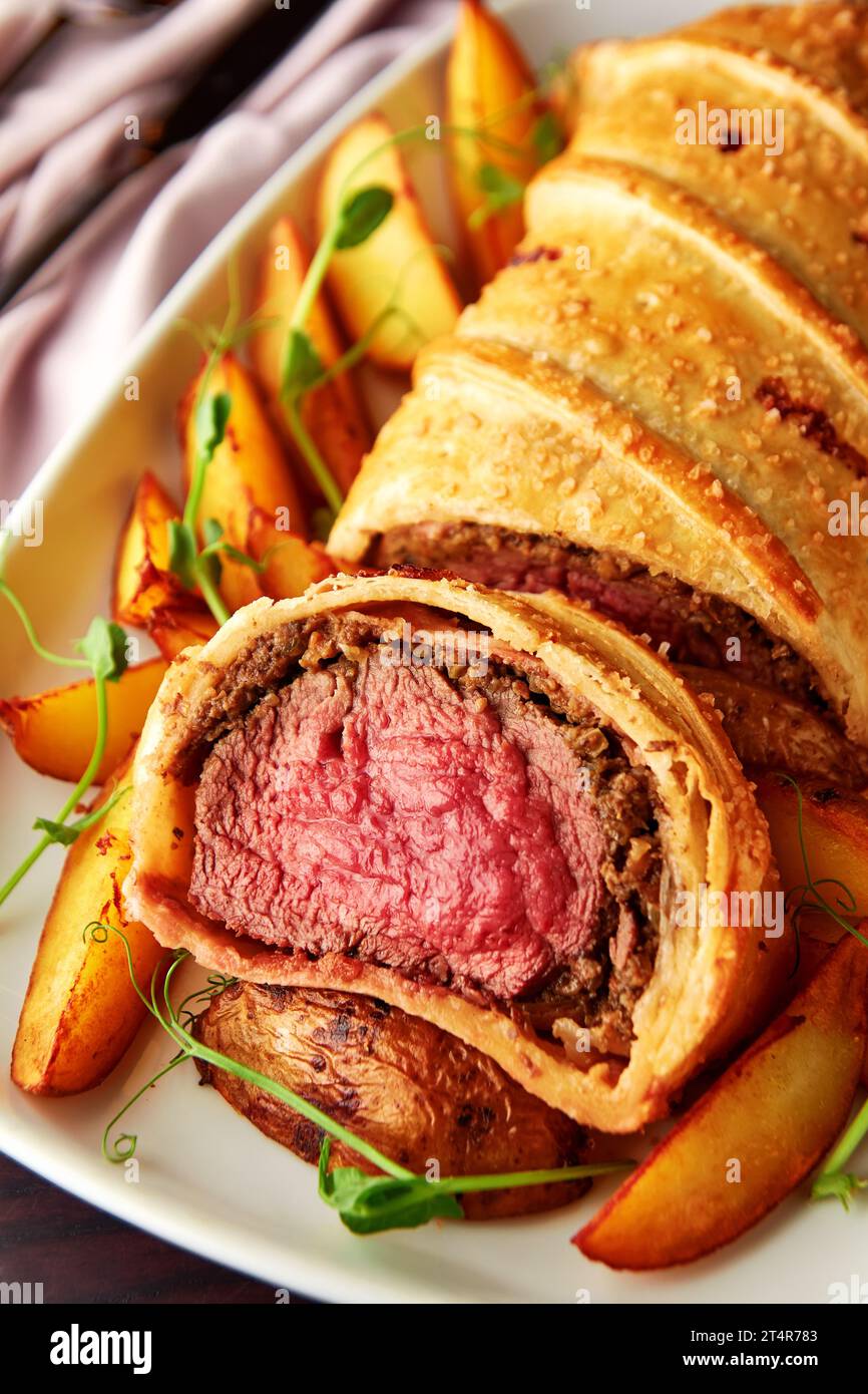 Delicious beef wellington served with baked potato and microgreens ...