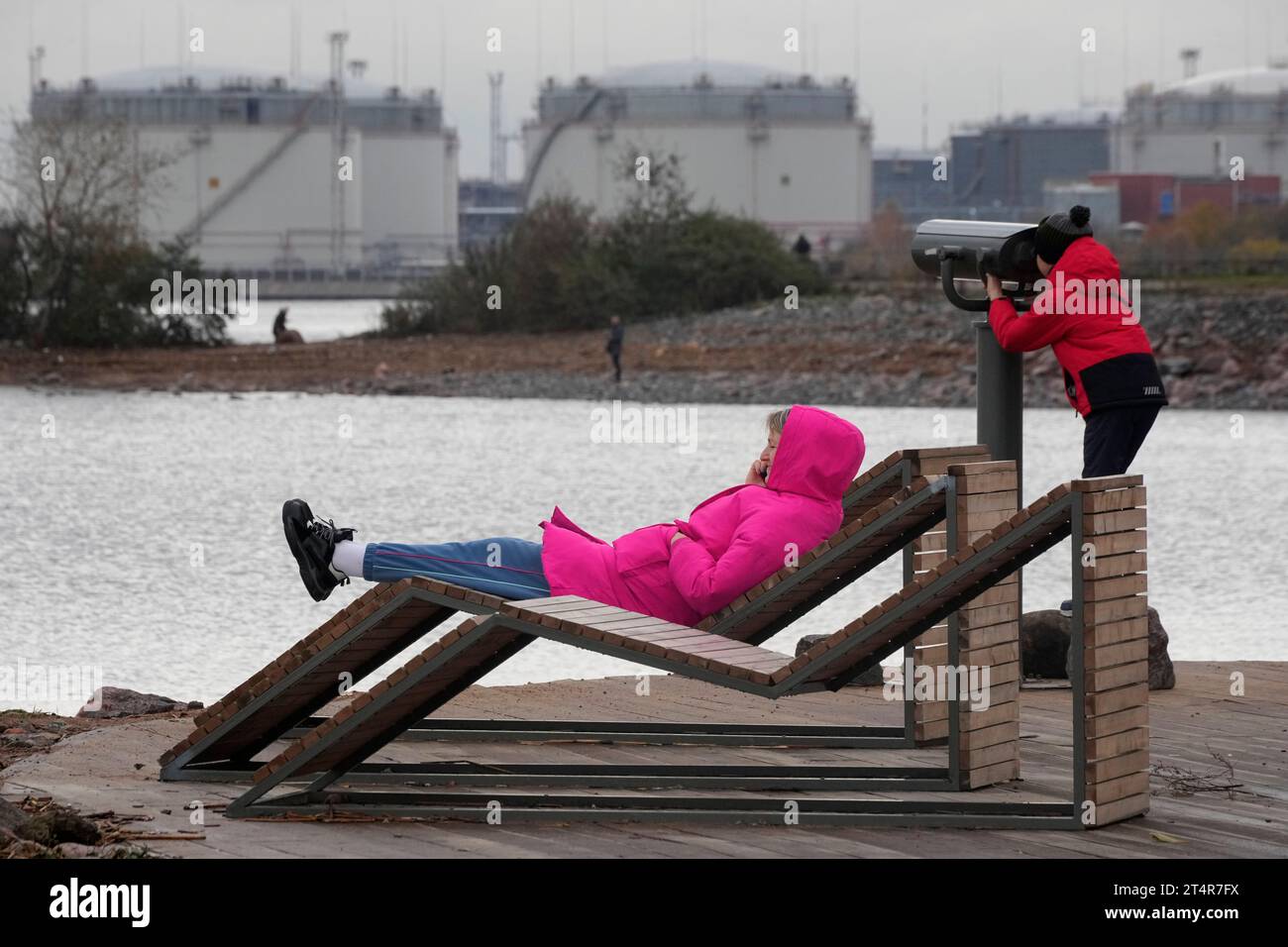 A woman sits at a beach lounger at the coast of the Gulf of Finland in ...