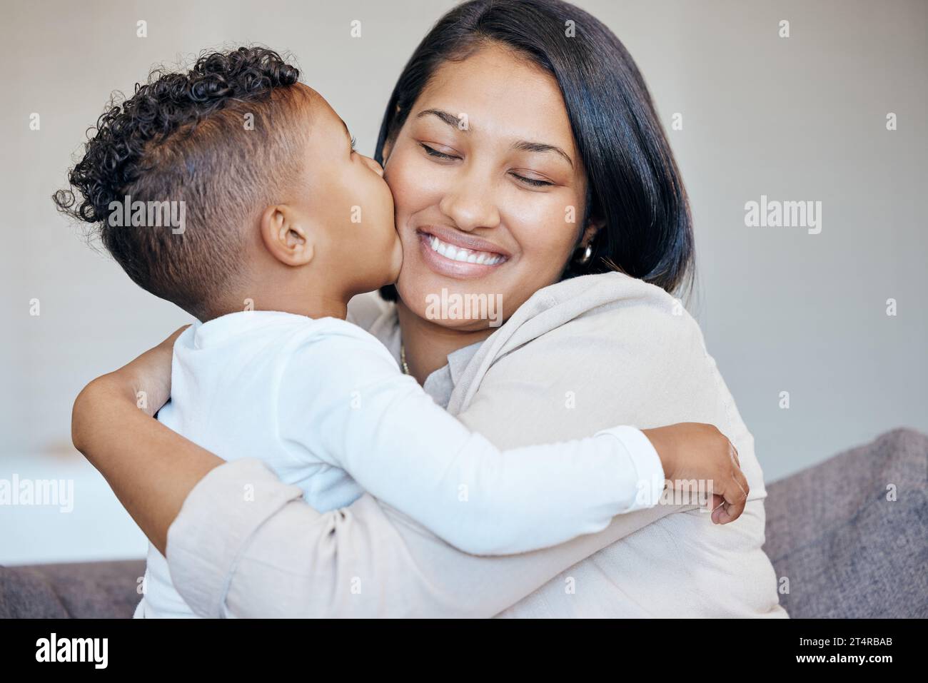 Adorable little boy kissing his mother on the cheek. Happy mixed race ...