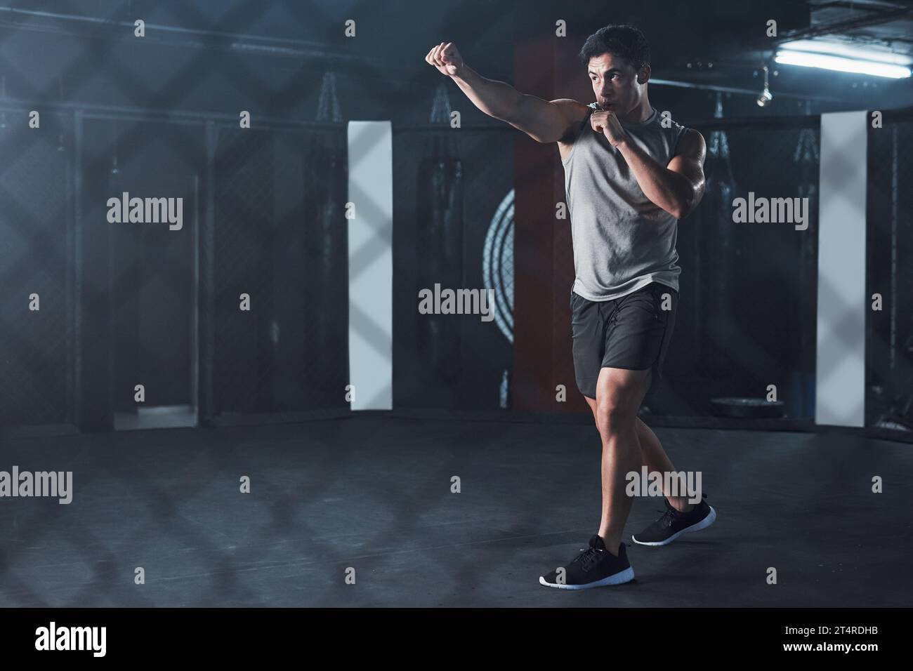 Health is power. a young man practicing his kickboxing routine at a gym ...