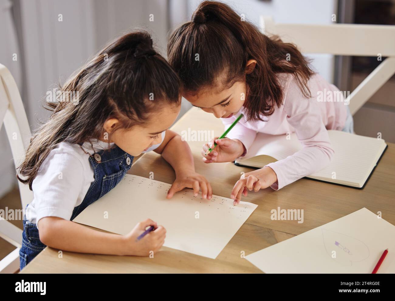 Two girls playing together. two girls completing their homework ...
