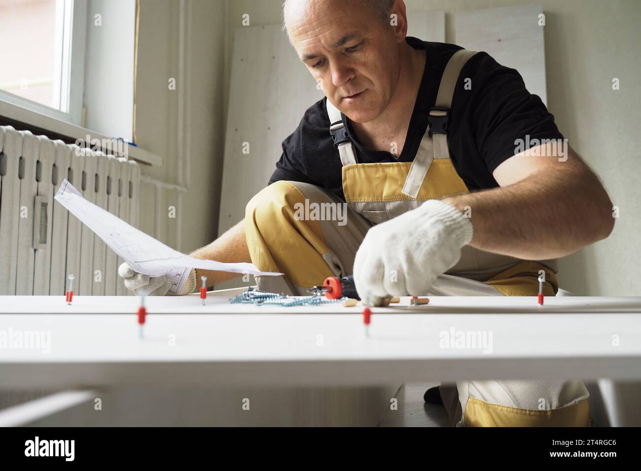A male worker studies instructions before assembling furniture. Overall ...