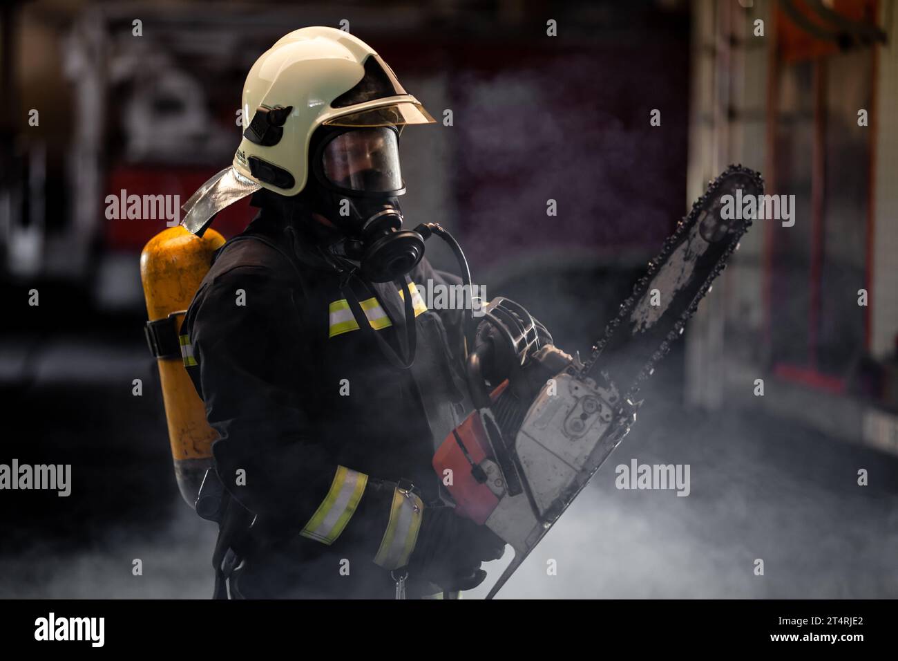 Firefighter portrait wearing full equipment, oxygen mask and chain saw ...