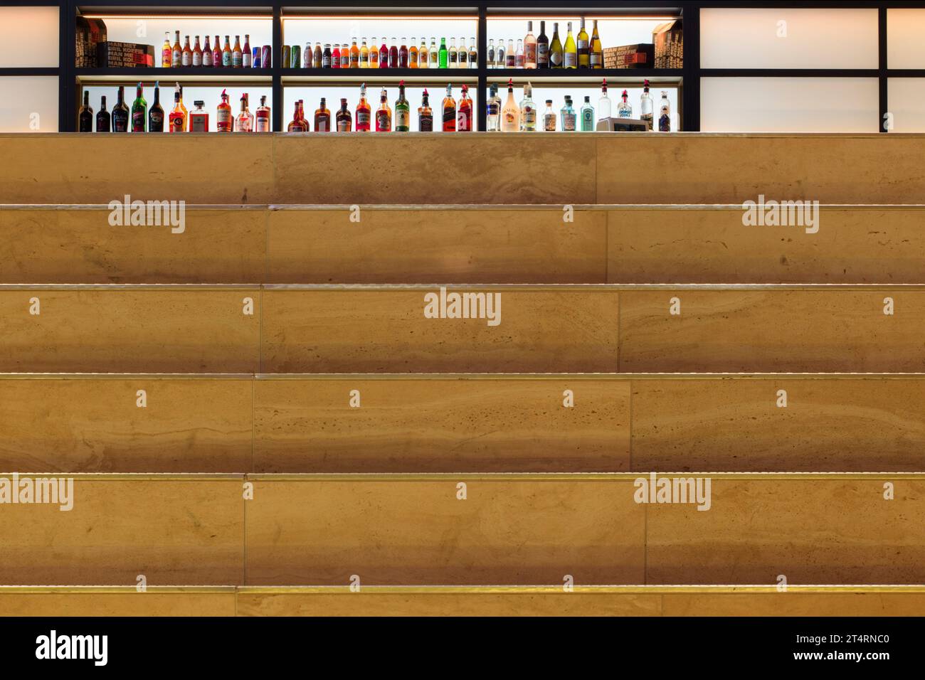 Timber staircase leading to bar in foyer, with backlit spirits bottles ...