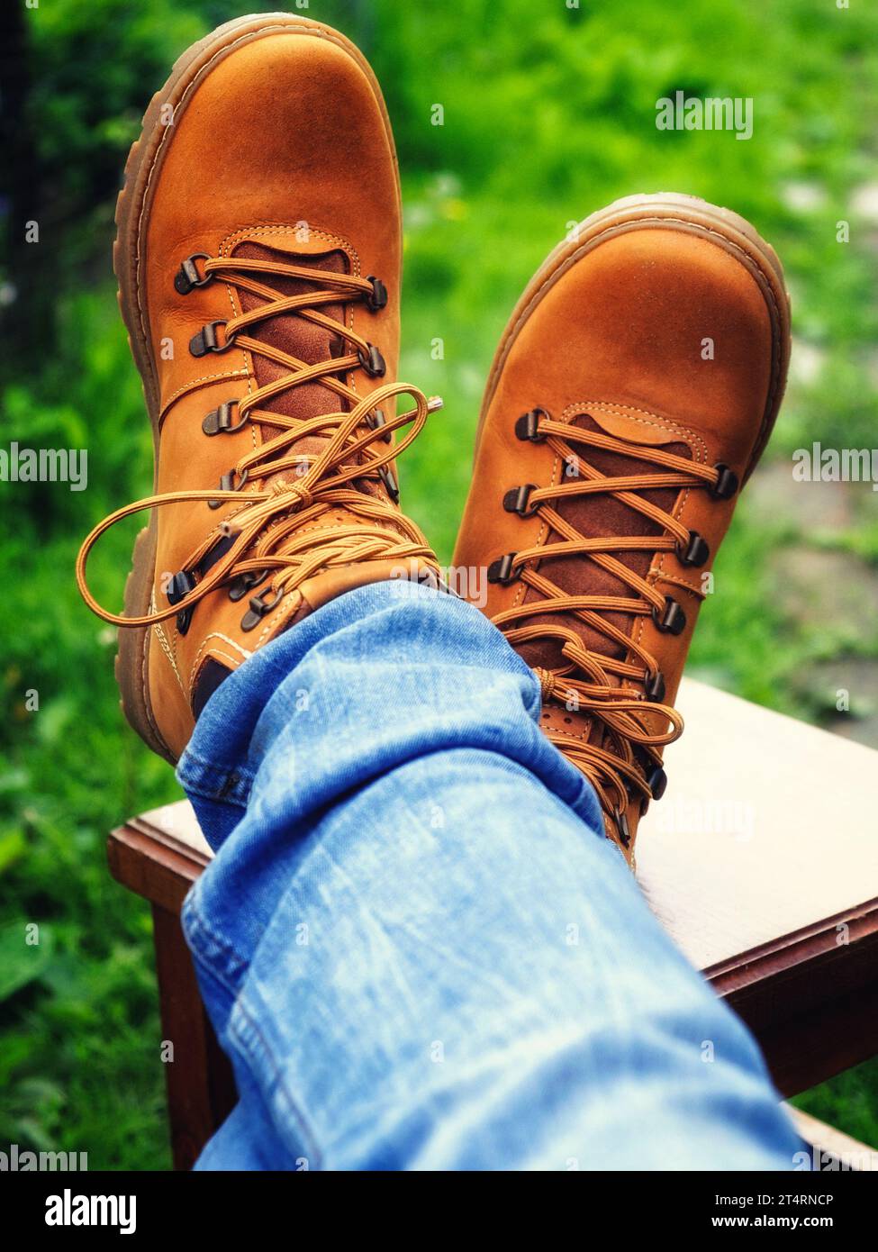 Brown boots and jeans on the legs. Legs are crossed on the stool Stock ...